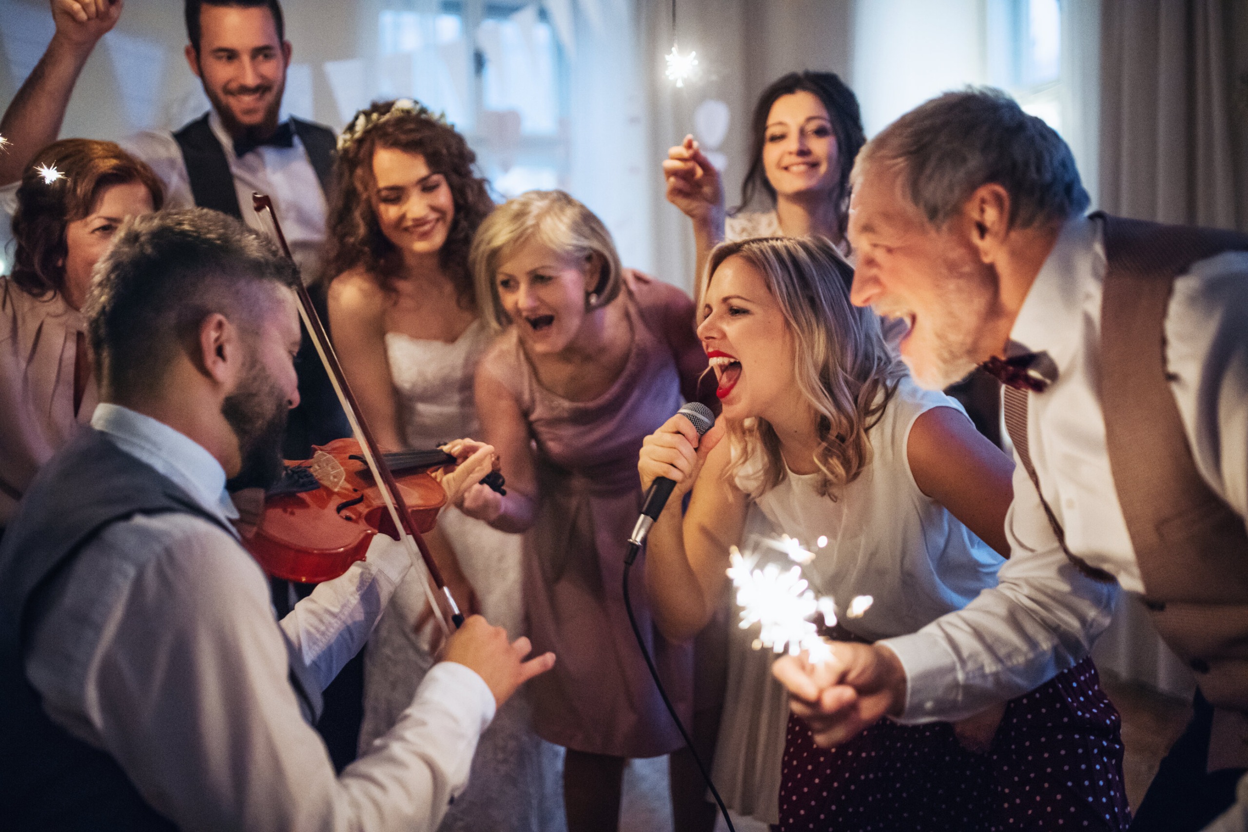 A young bride, groom and other guests dancing and singing on a wedding ...